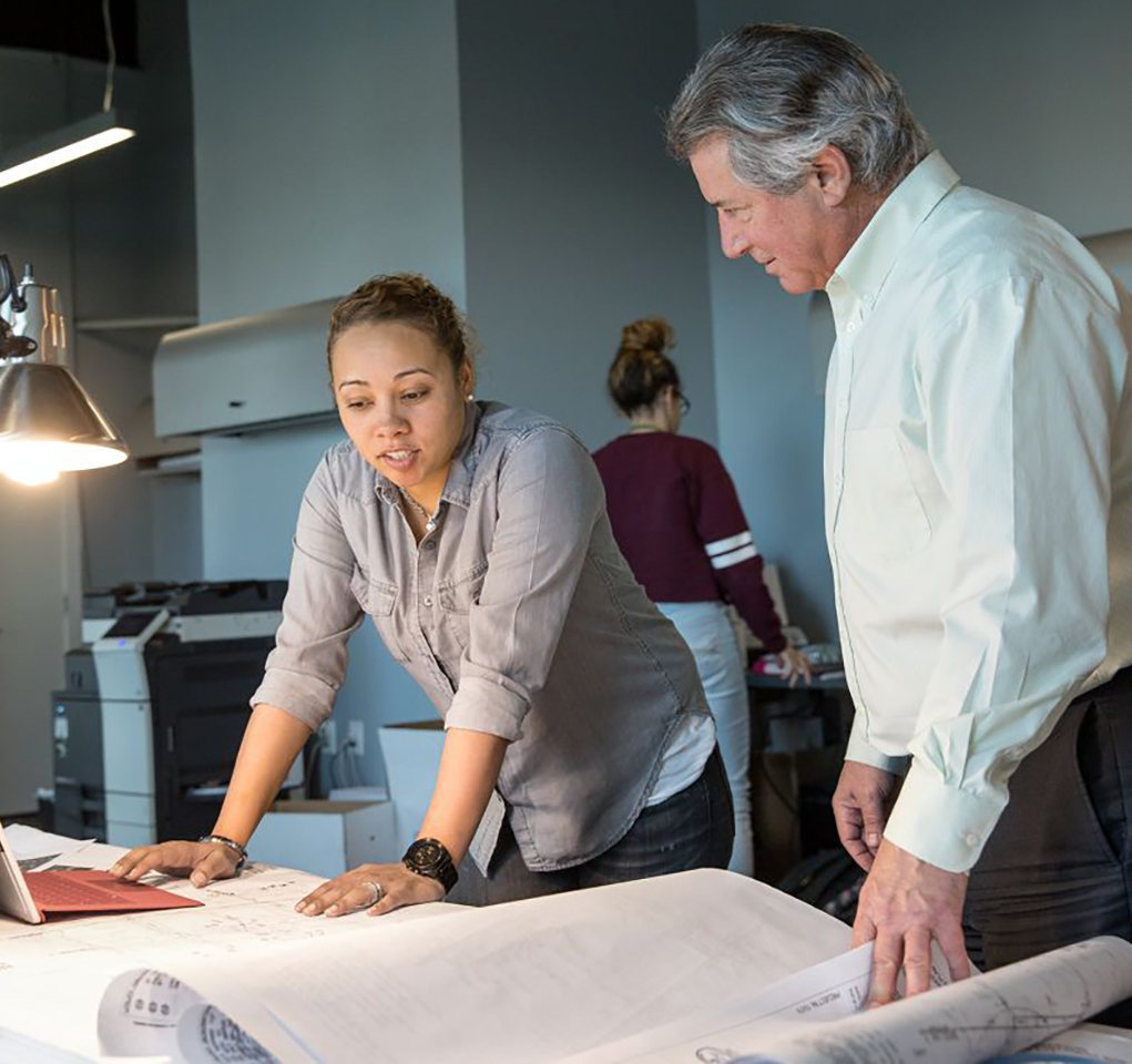Two people discussing charts on paper in front of them.